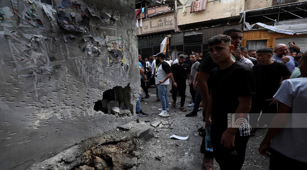 مواطنون يتفقدون مكان قصف طائرة مسيرة للاحتلال مجموعة مواطنين في حارة ...